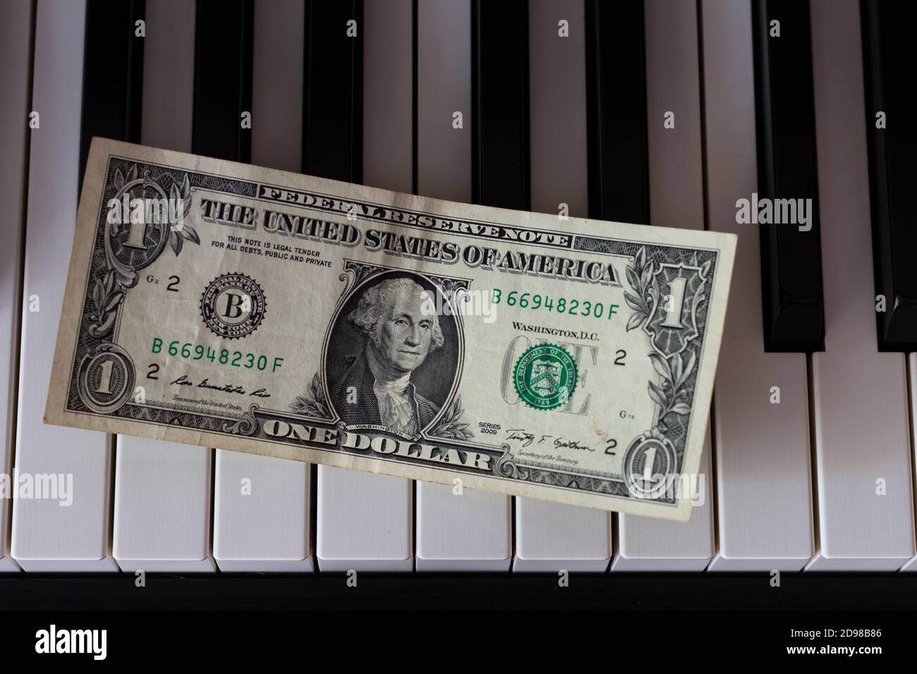 One dollar banknote lying on the piano keys. The dollar as a symbol of ...