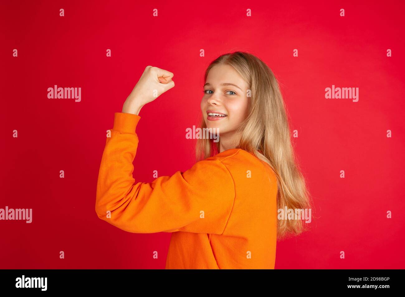 Strong, power. Portrait of young caucasian woman isolated on red studio ...