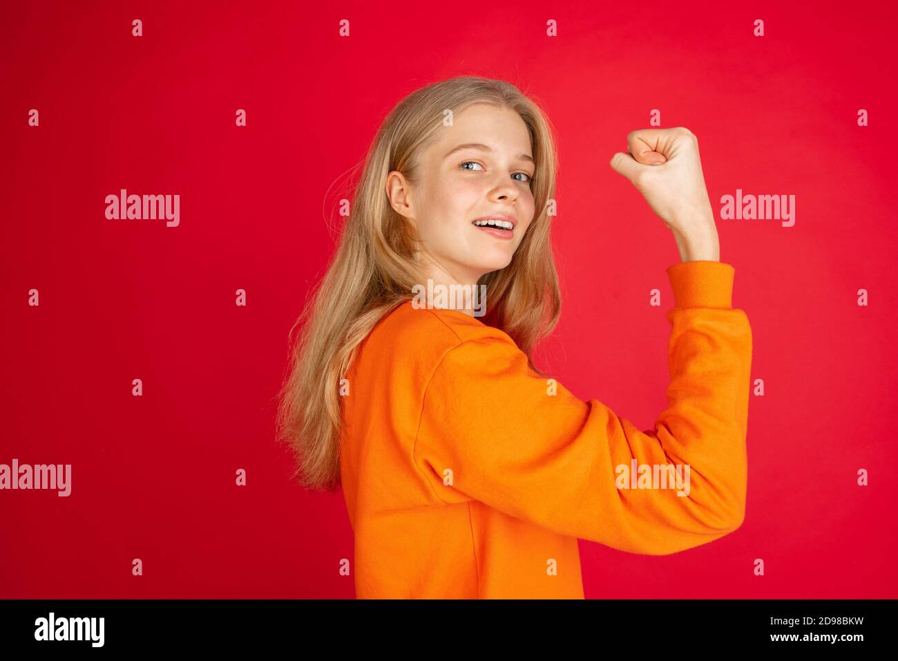 Strong, power. Portrait of young caucasian woman isolated on red studio ...