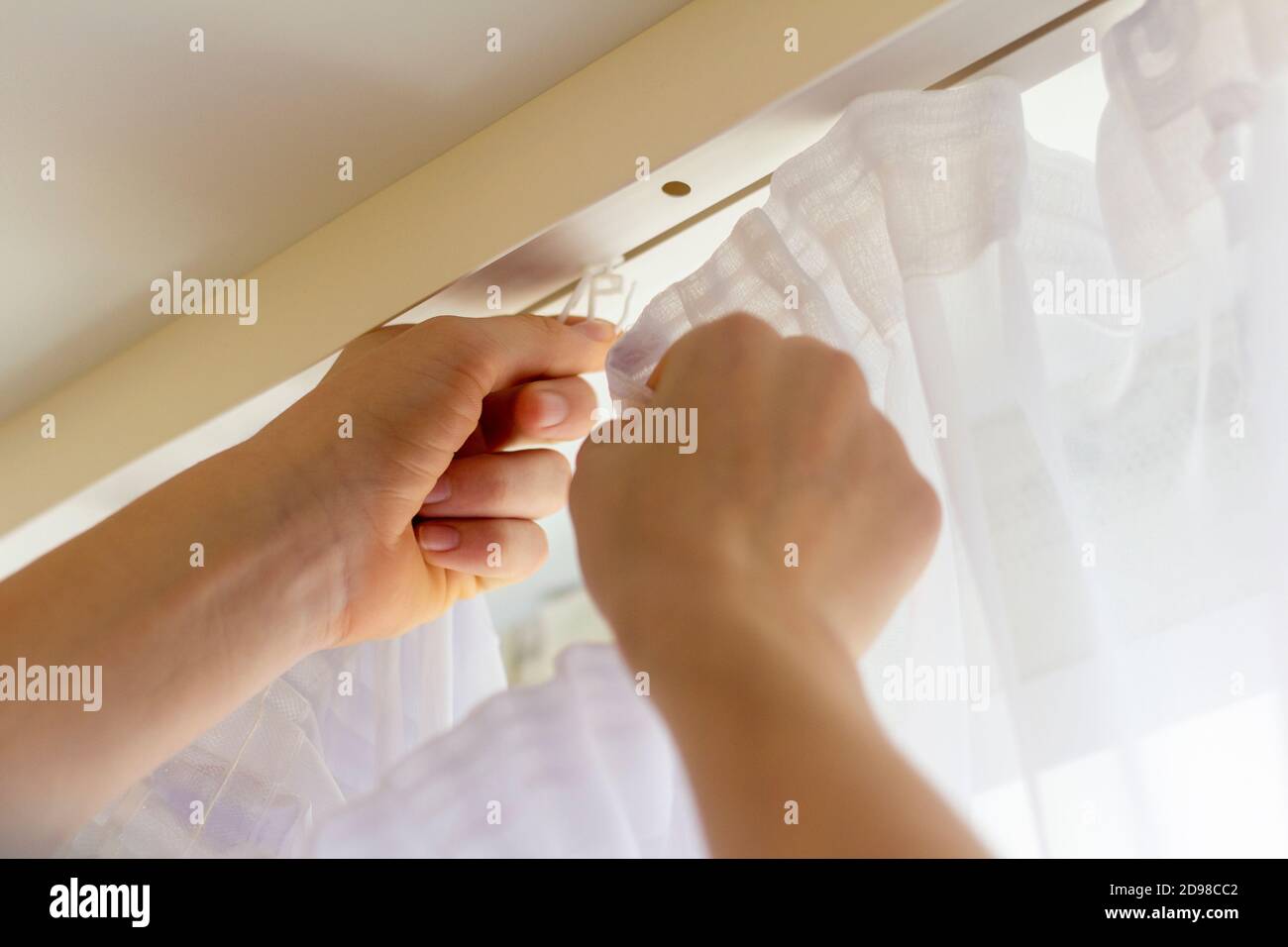 Hands of a young man hang curtains on the ledge on the window Stock ...