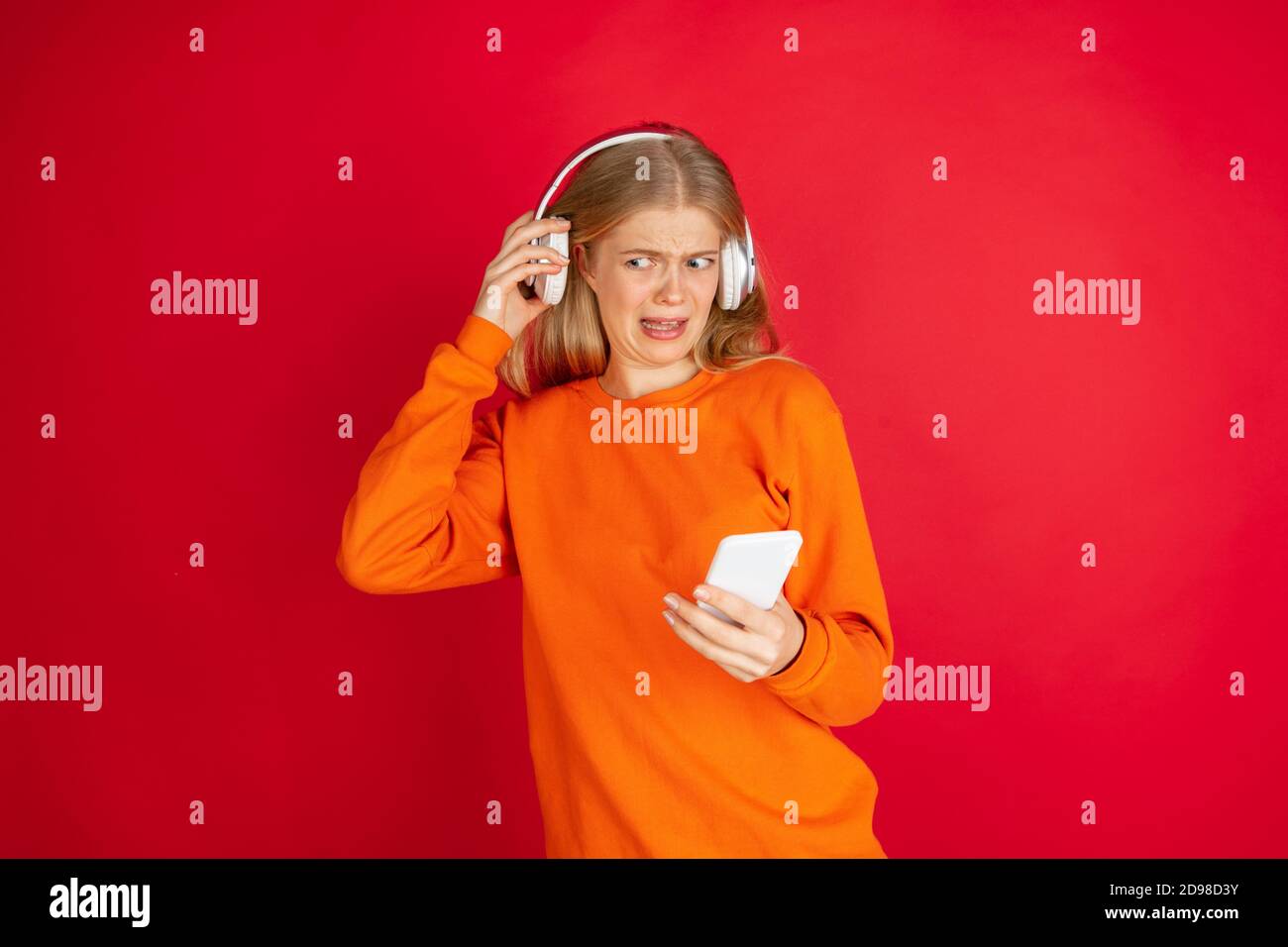 Listening to music with headphones, terrified. Portrait of young woman ...