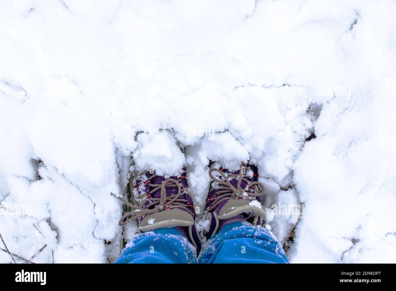 Female feet in winter boots standing in a snowdrift of fresh snow ...