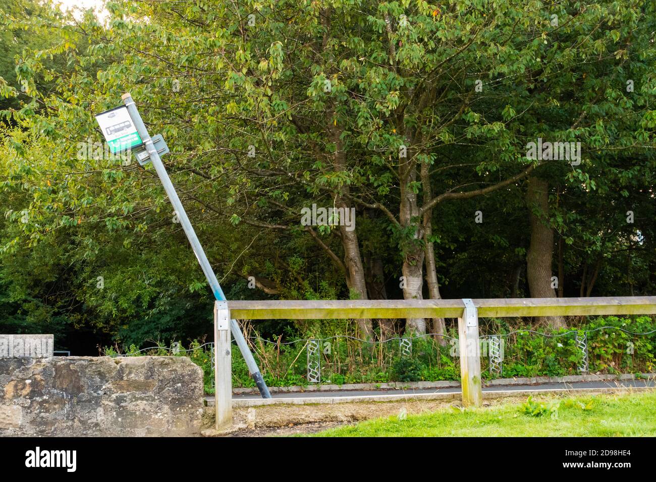 A bus stop sign that has been hit by a car and is bent over at an angle ...