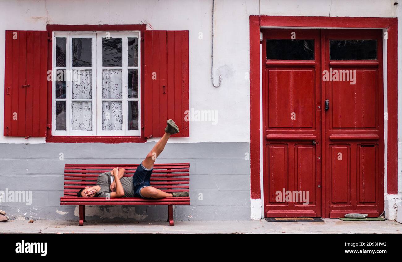 Young adult laying on a bench in front of a typical Basque Country's ...
