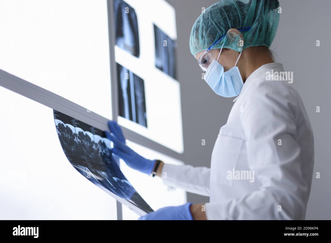 Doctor in office in protective medical mask and glasses looks at X-ray ...