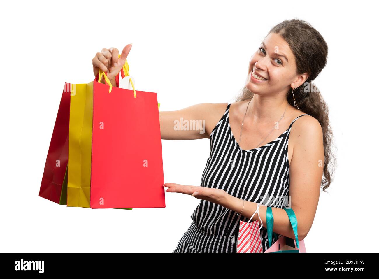 Cheerful female model smiling presenting colourful shopping bags ...
