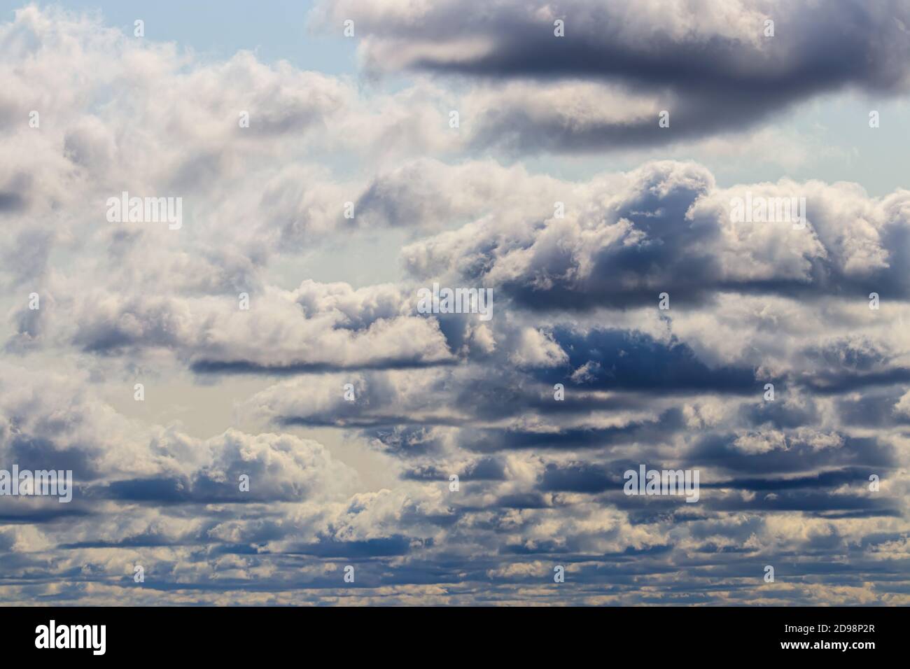 Bright blue sky with dramatic cumulus clouds lit by the daytime sun ...