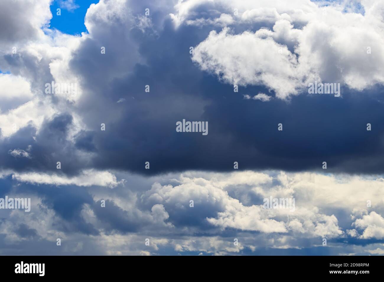 Bright blue sky with dramatic cumulus clouds lit by the daytime sun ...