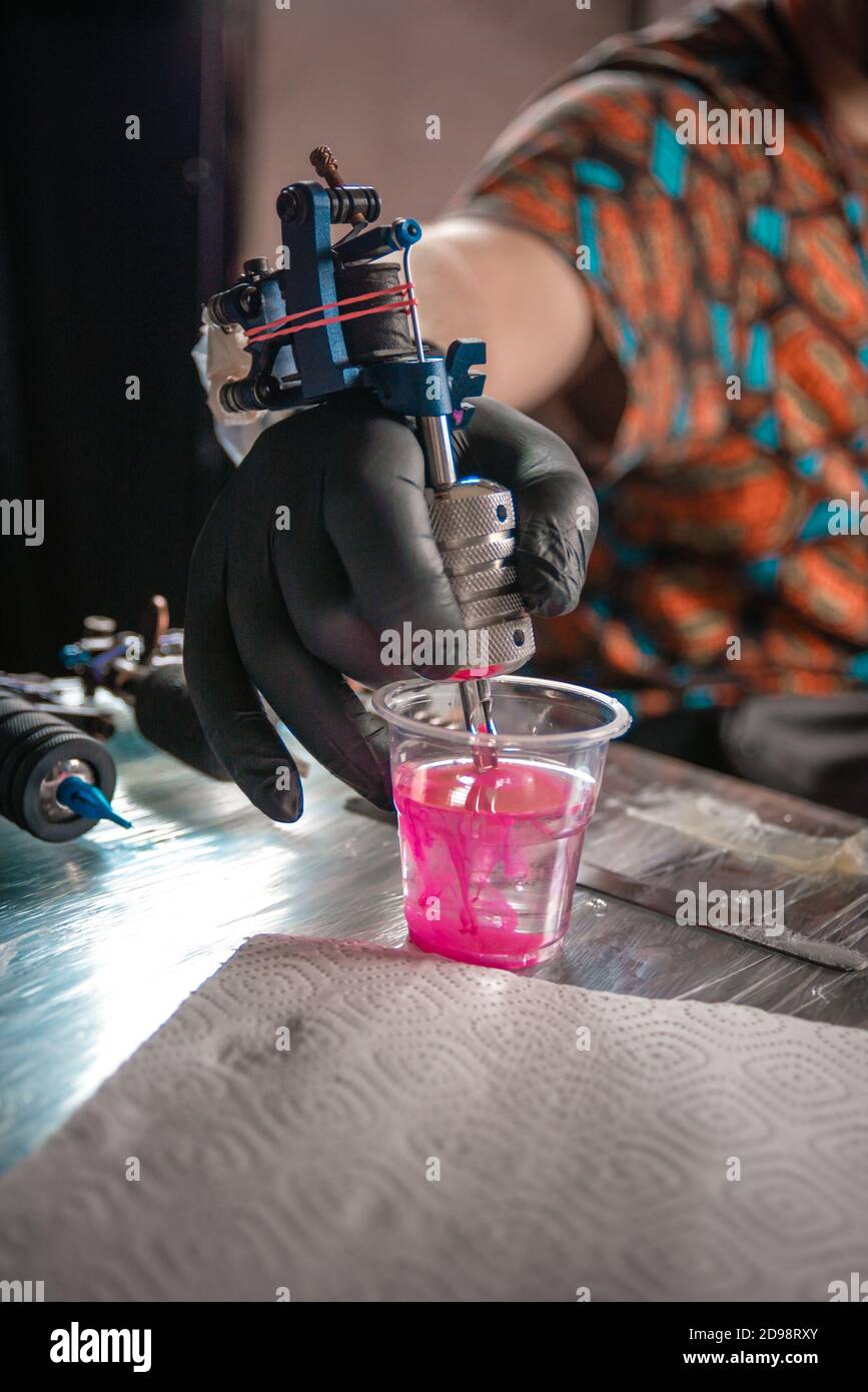 Hand of tattooer and a tattoo machine Stock Photo - Alamy