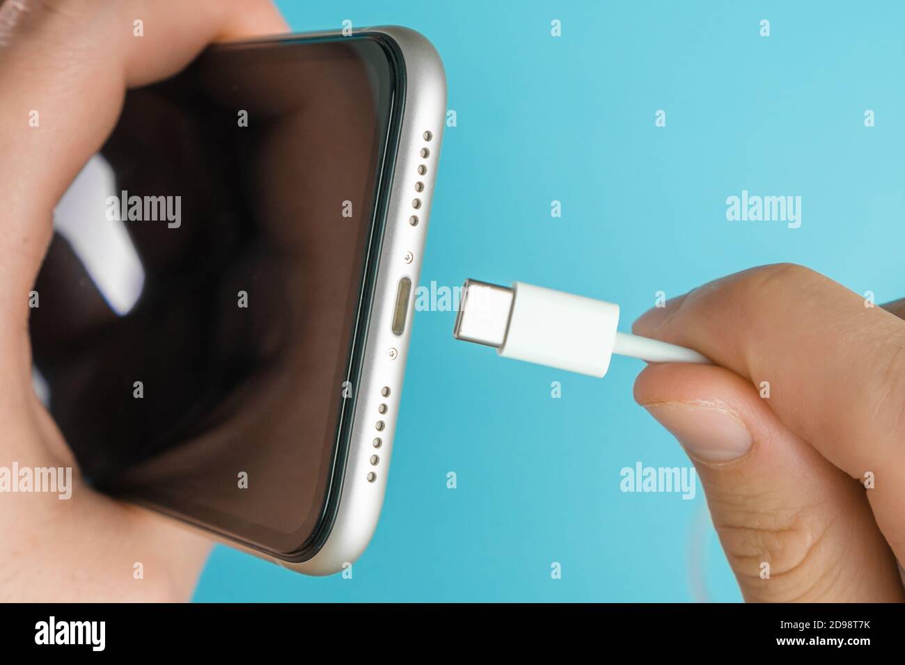 Close up mans hand inserting a charger into the mobile phone through a ...