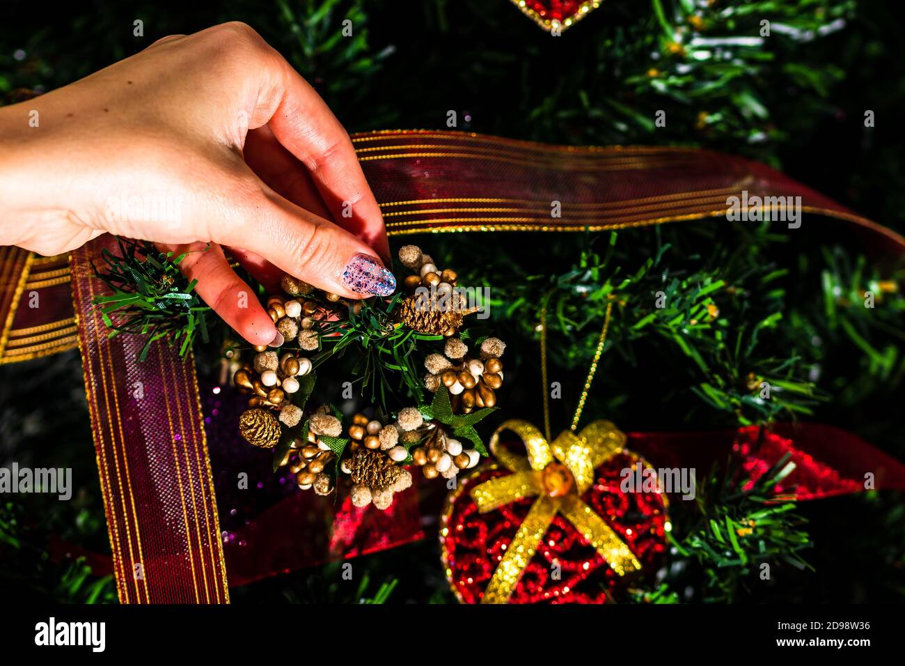 Decorating Christmas tree, hand putting Christmas decorations on fir ...
