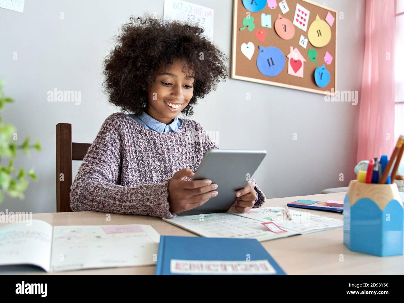 Smiling african american kid girl holding digital tablet elearning at ...