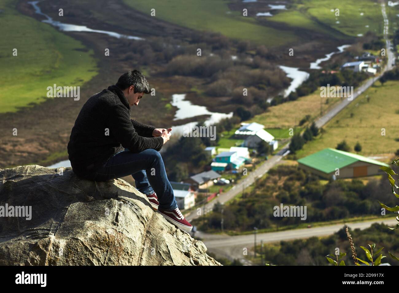 Young male looks at the city on a rock from above Stock Photo - Alamy