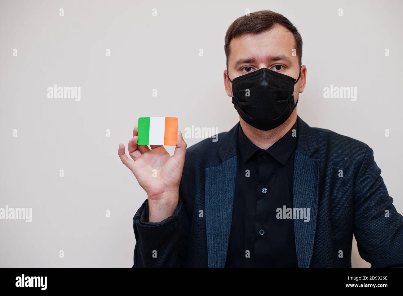 European man wear black formal and protect face mask, hold Ireland flag ...
