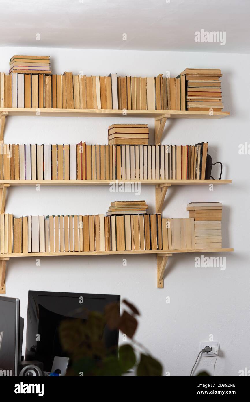 Light wooden bookshelves with hardback overturned books in white ...