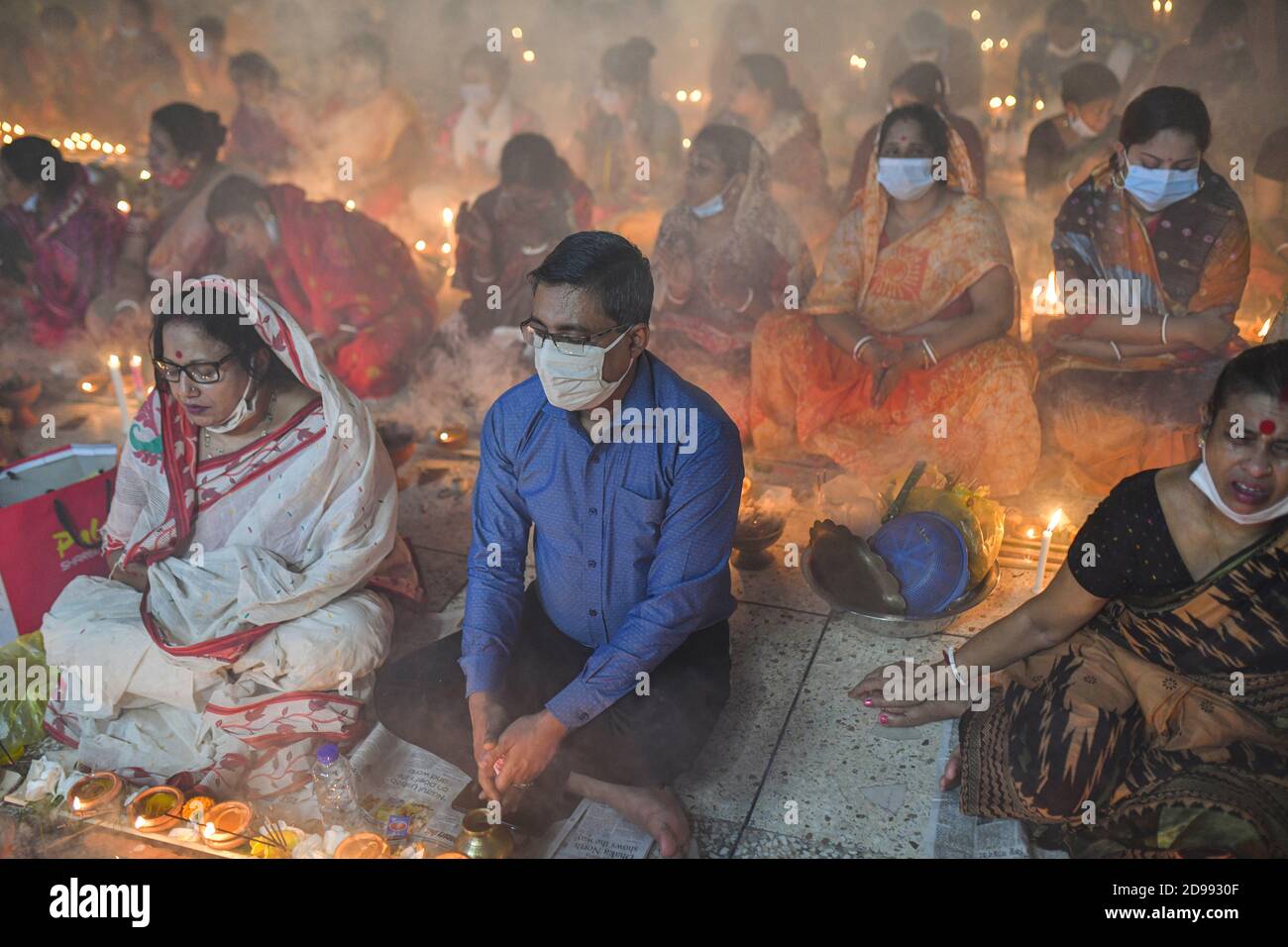 Hindu devotees sit on the floor to worship with Prodip and candle ...