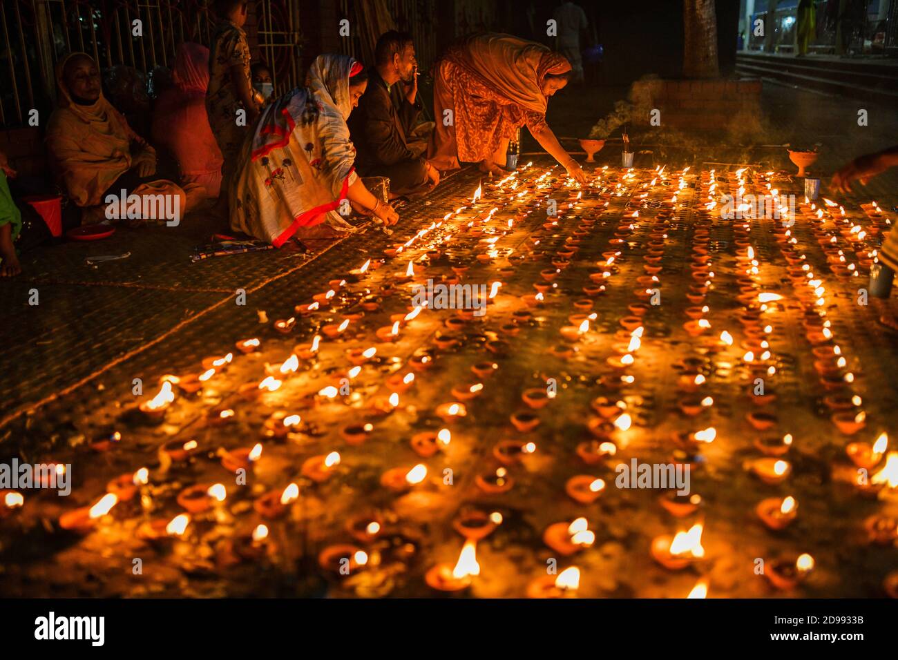 Hindu devotees sit on the floor to worship with Prodip and candle ...