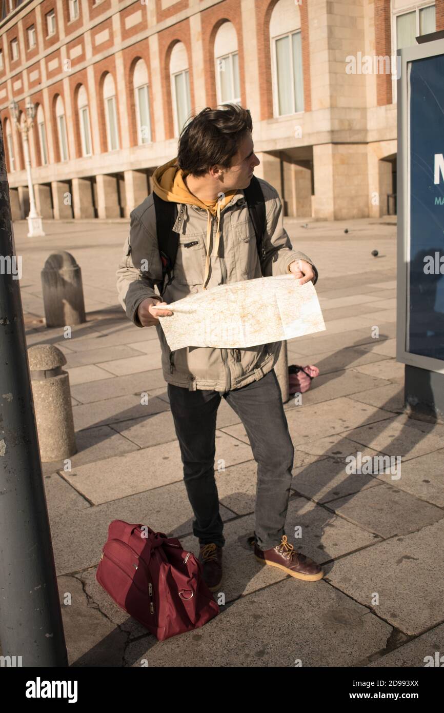 Young male tourist with a backpack and a bag checking the way on the ...