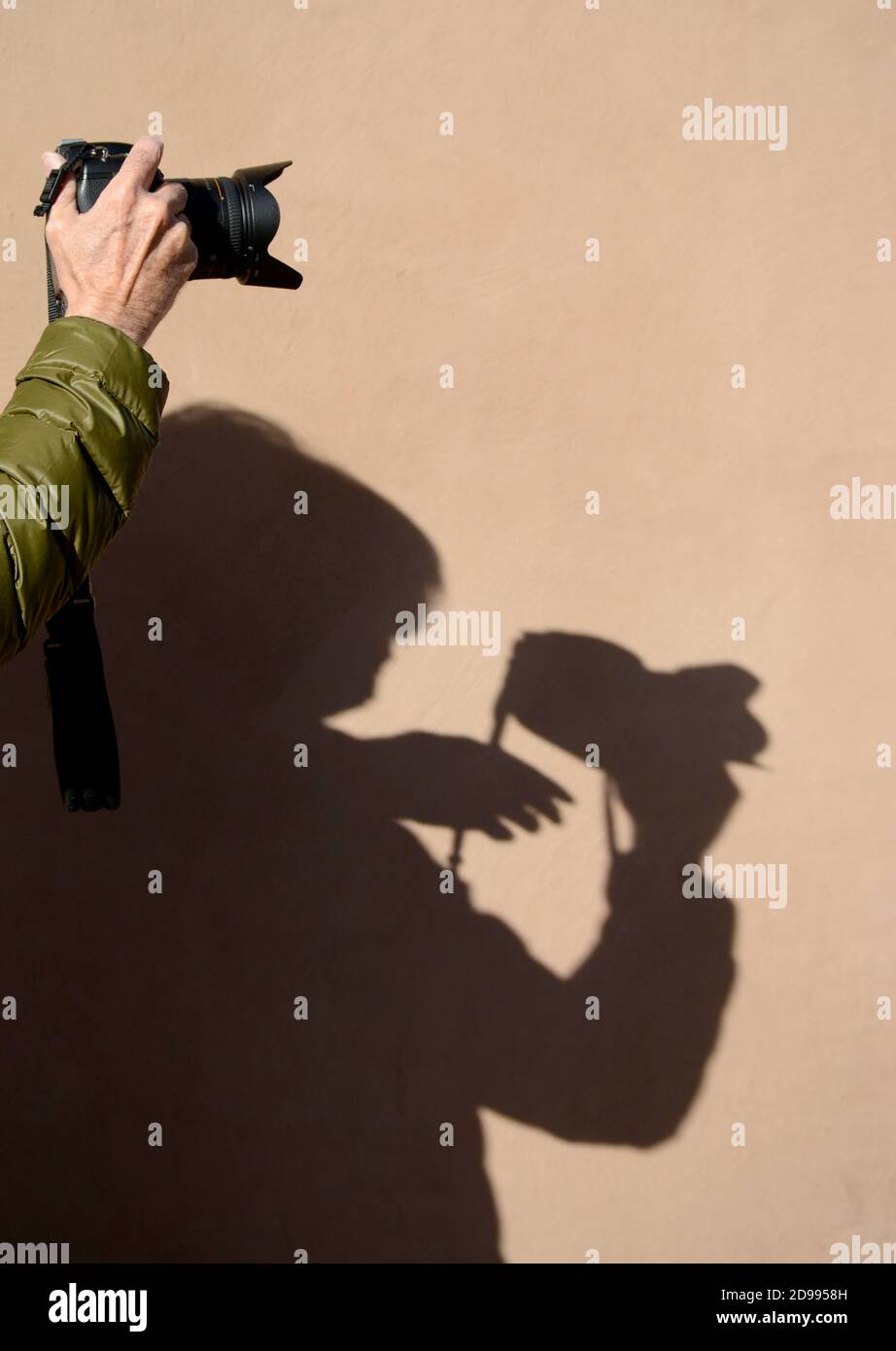 A tourist taking photographs casts a shadow on an adobe wall in Santa ...