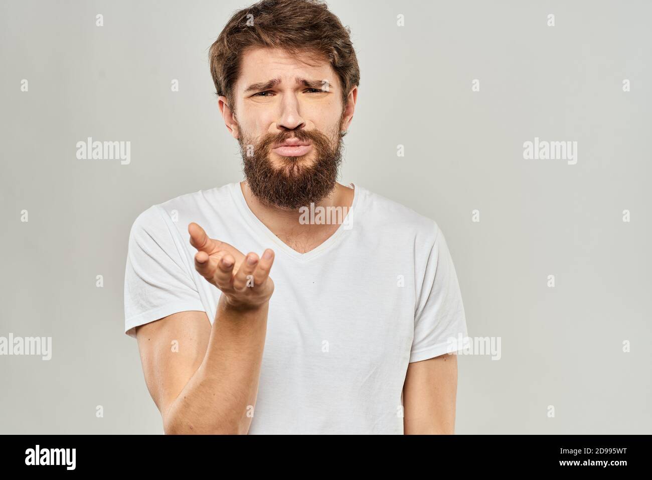 A man in a white t-shirt with a beard emotions displeased facial ...