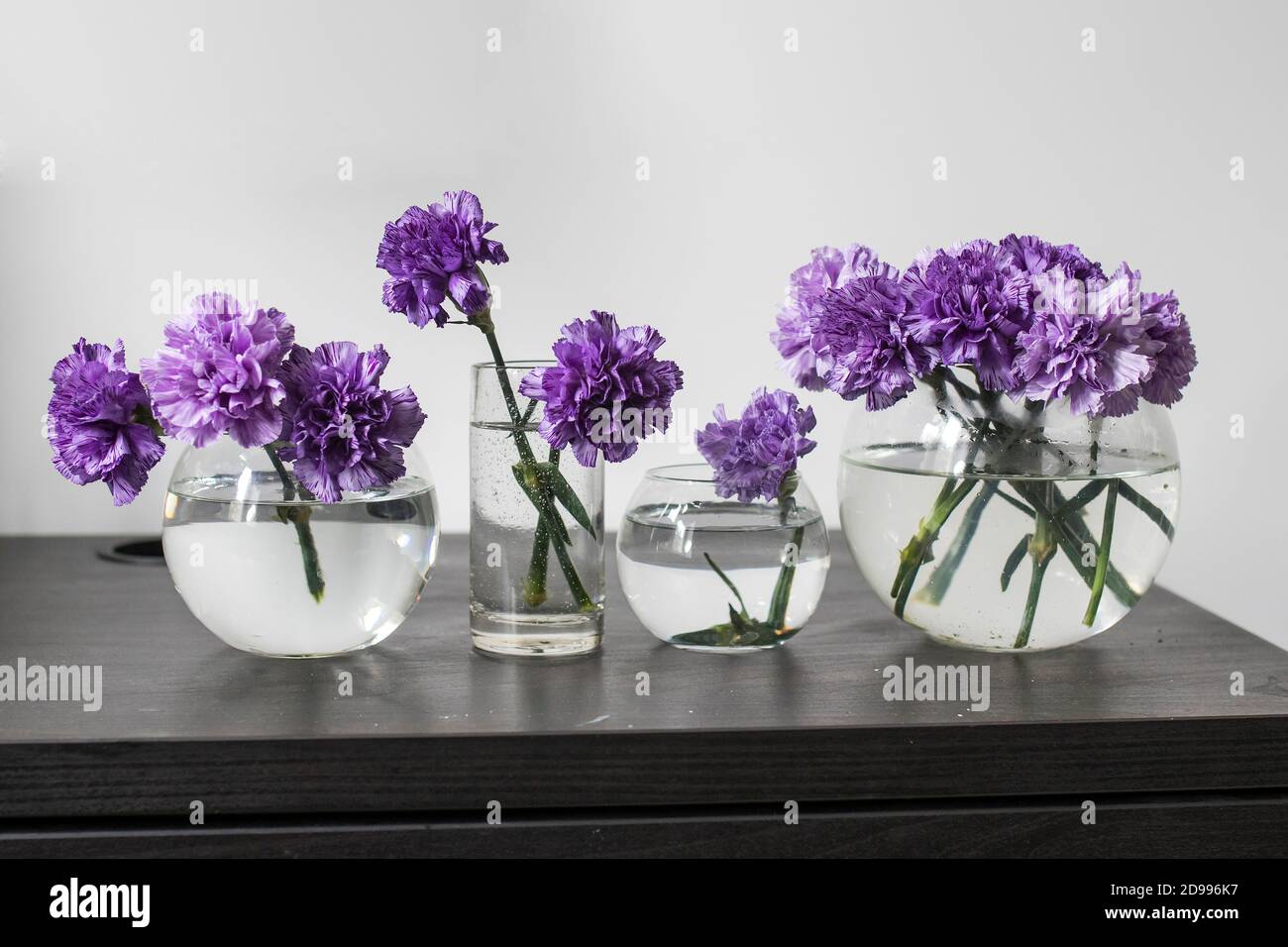 Bridal bouquets of lilac carnations in a four round glass vases ...