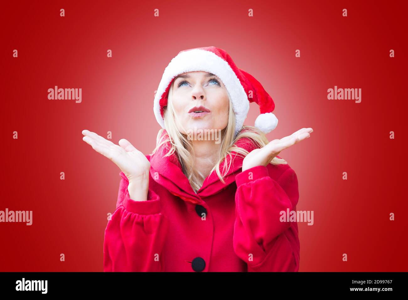 blond woman dressed as Santa Claus on a red background looking up Stock ...