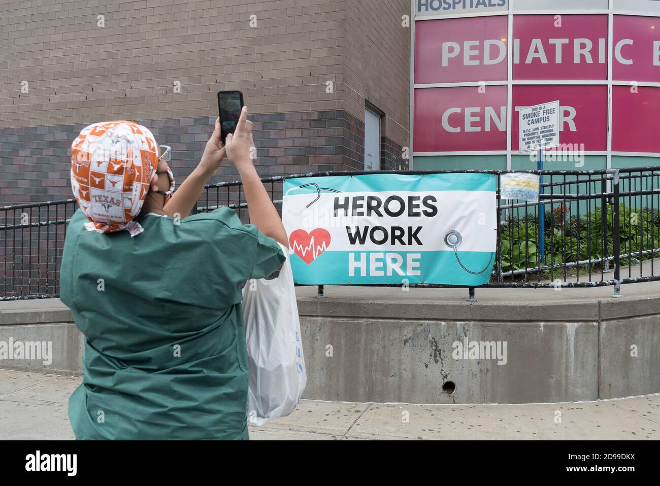 A hospital worker wearing a face mask takes a picture of a sign ...