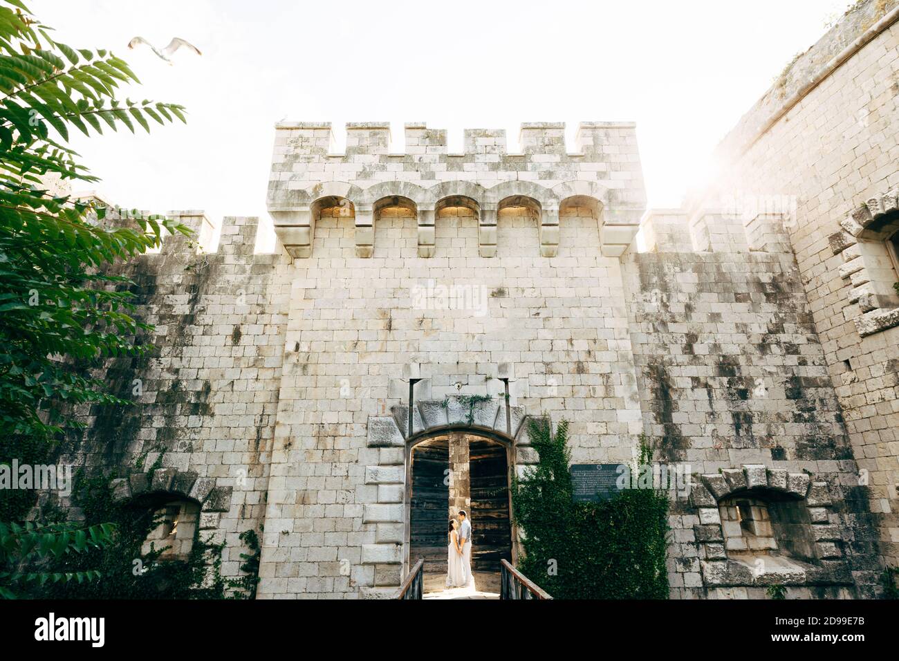 bride and groom are hugging at the ancient gate near the Arza fortress ...