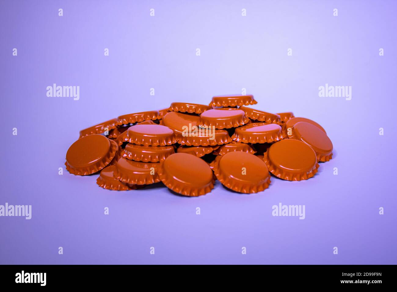 Close up orange crown caps for beer and soda. Behind there is a white ...