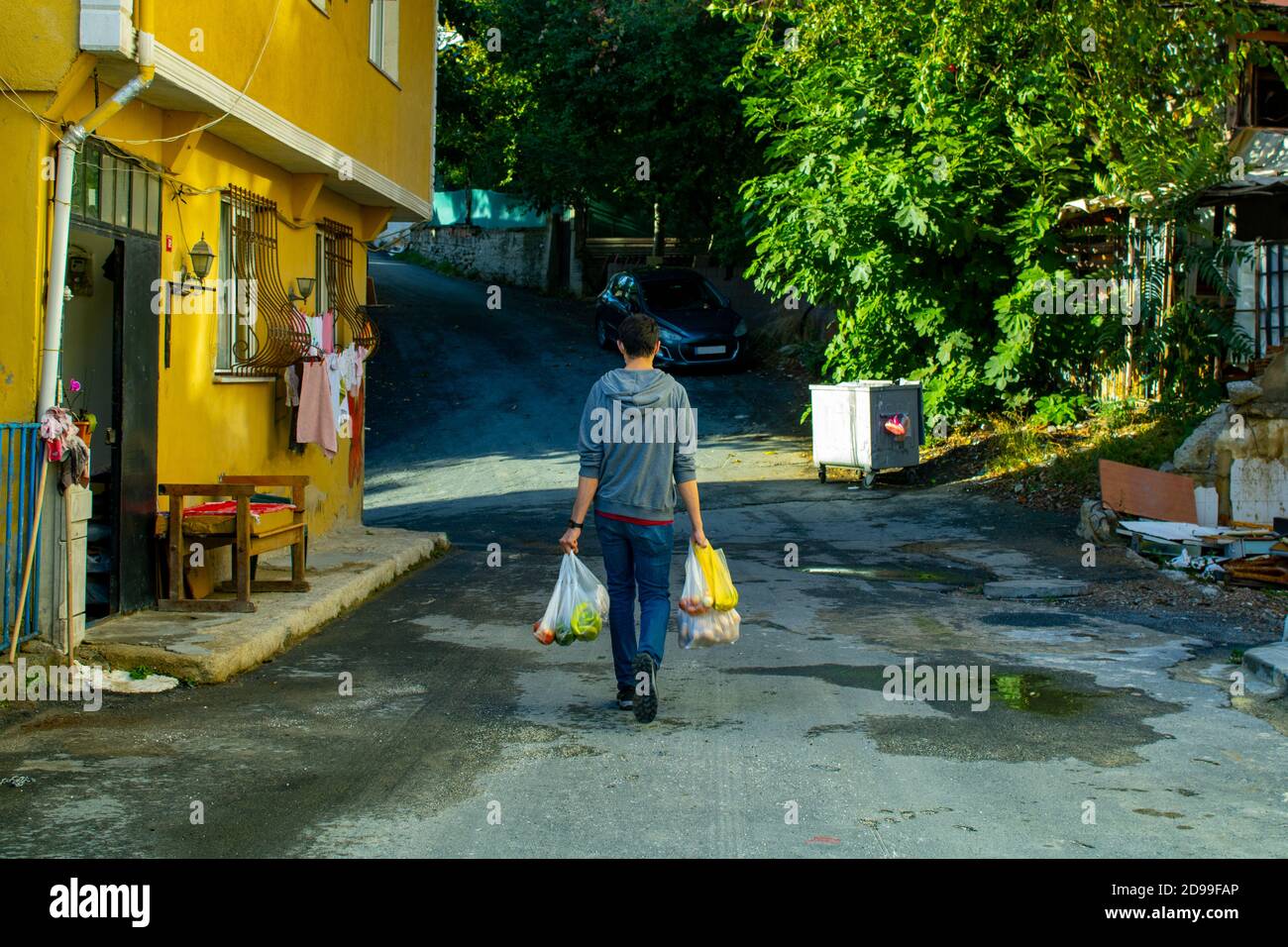 Groceries are in plastic bags in the hands of a man who is coming back ...