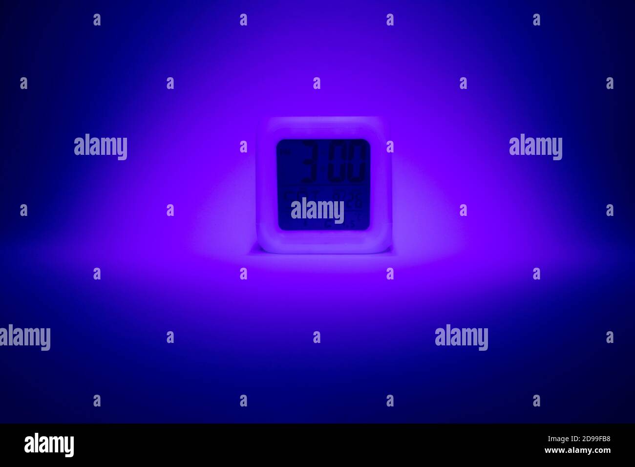 A digital alarm clock showing 3 o'clock. Stylized background with ...