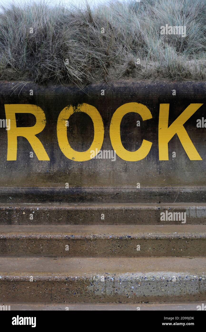 Yellow writing on concrete wall Stock Photo - Alamy