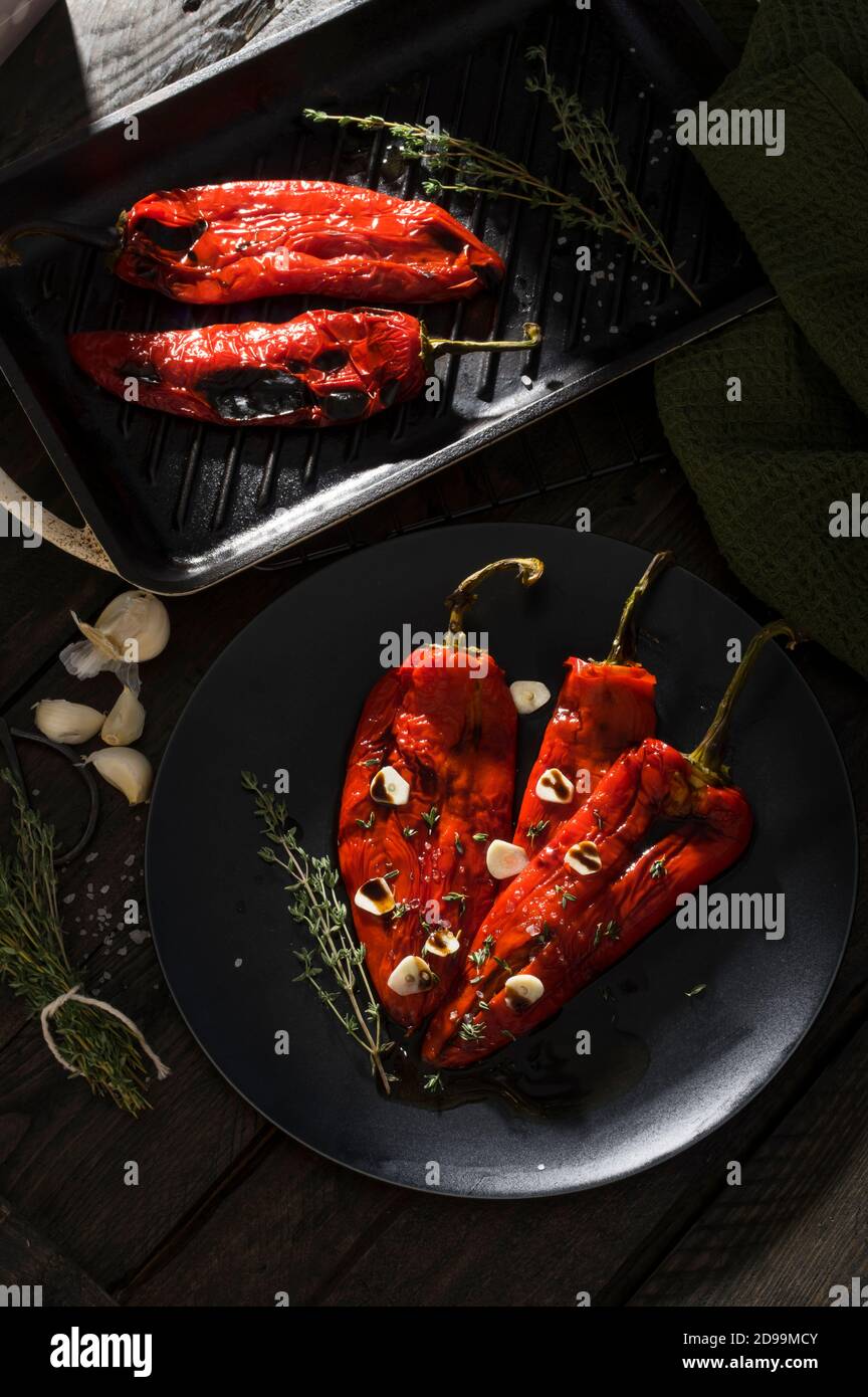 Roasted pointed red peppers with garlic and thyme spices on black Stock ...