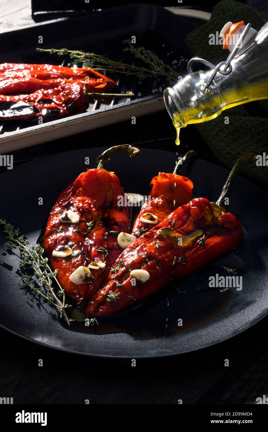 Roasted pointed red peppers with garlic and thyme spices on black Stock ...