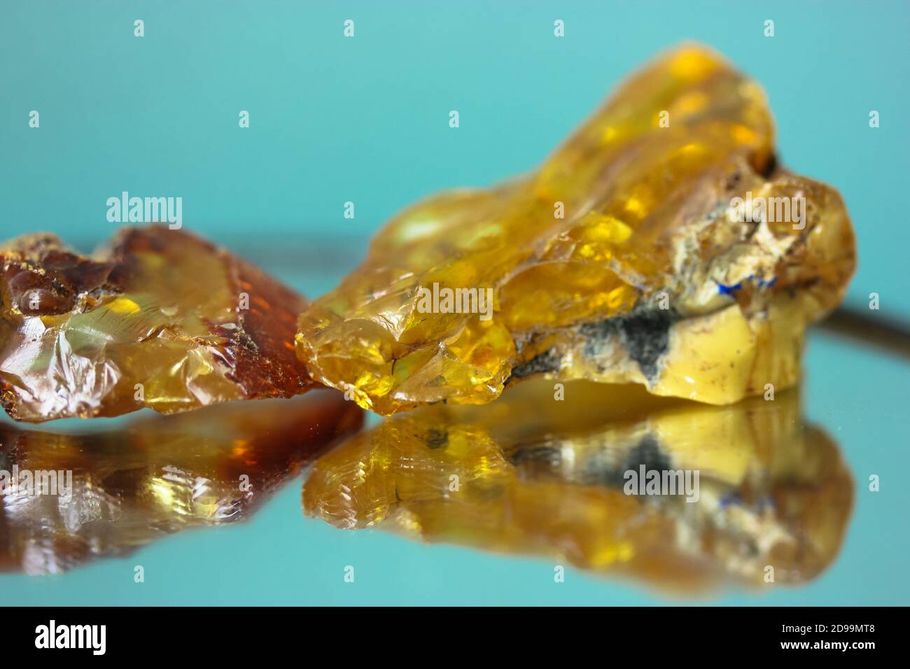 A piece of natural amber on a mirror surface, a reflection of a yellow ...