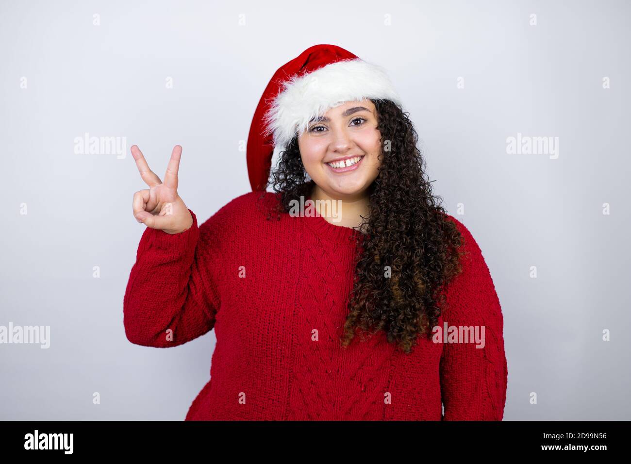 Young beautiful woman wearing a Santa hat over white background showing ...