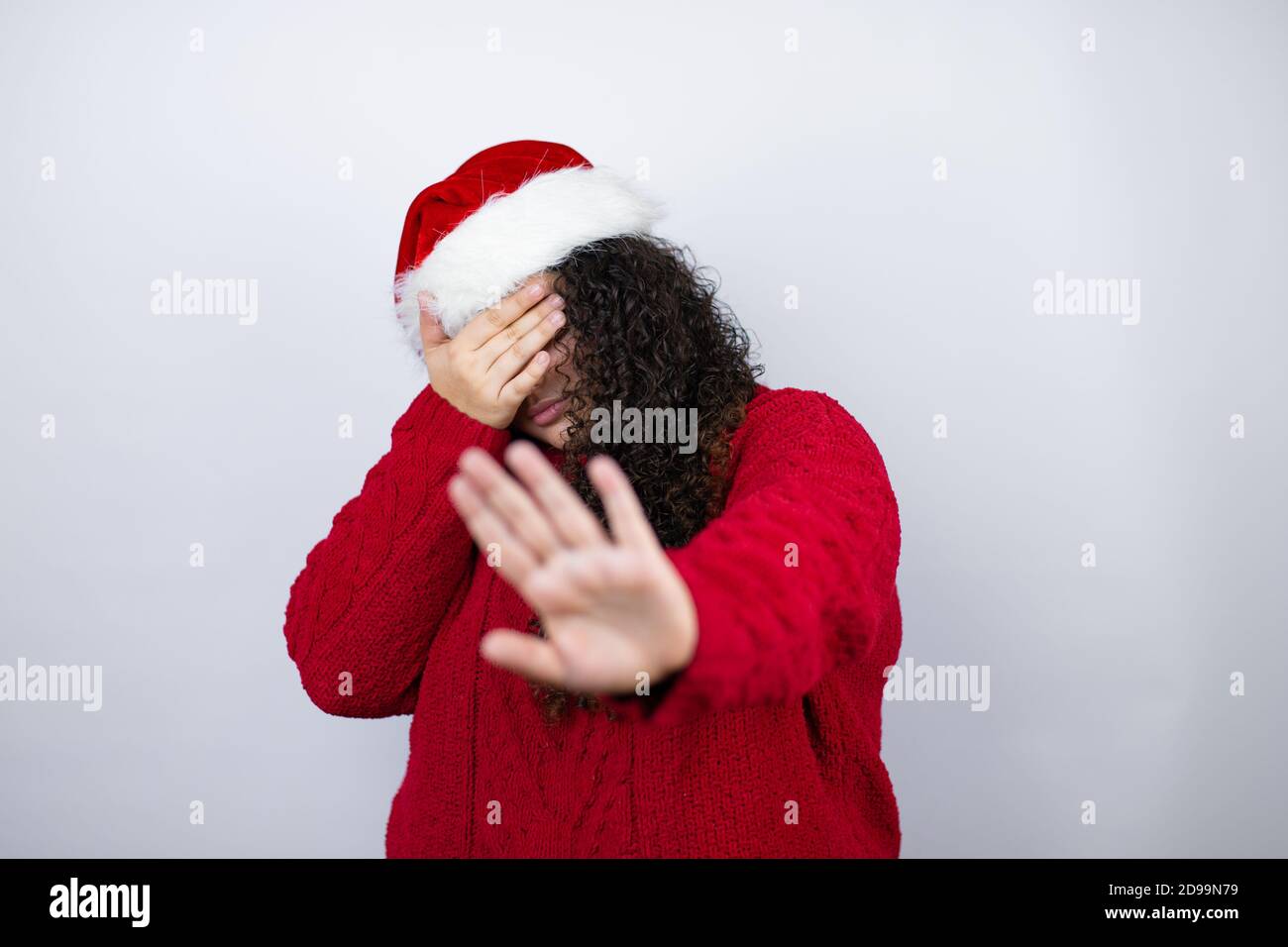 Young beautiful woman wearing a Santa hat over white background ...