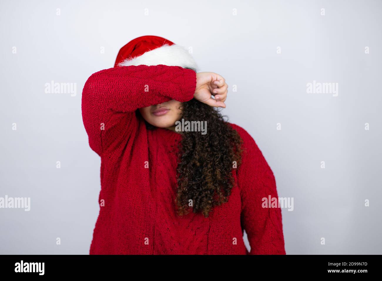 Young beautiful woman wearing a Santa hat over white background ...