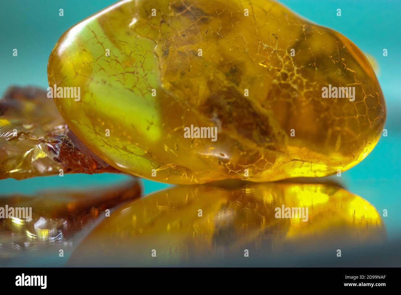 A piece of natural amber on a mirror surface, a reflection of a yellow ...