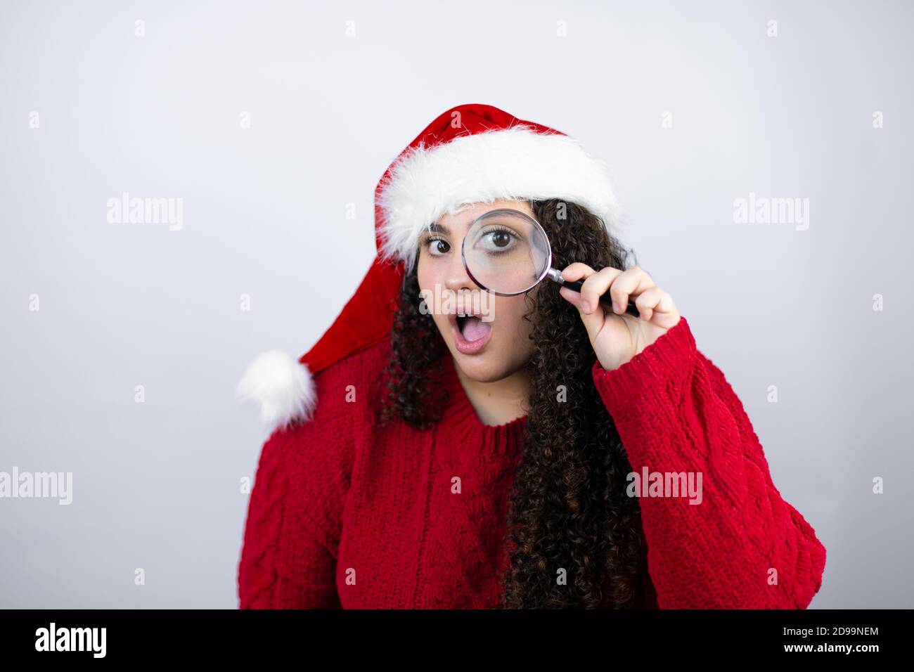 Young beautiful woman wearing a Santa hat over white background ...