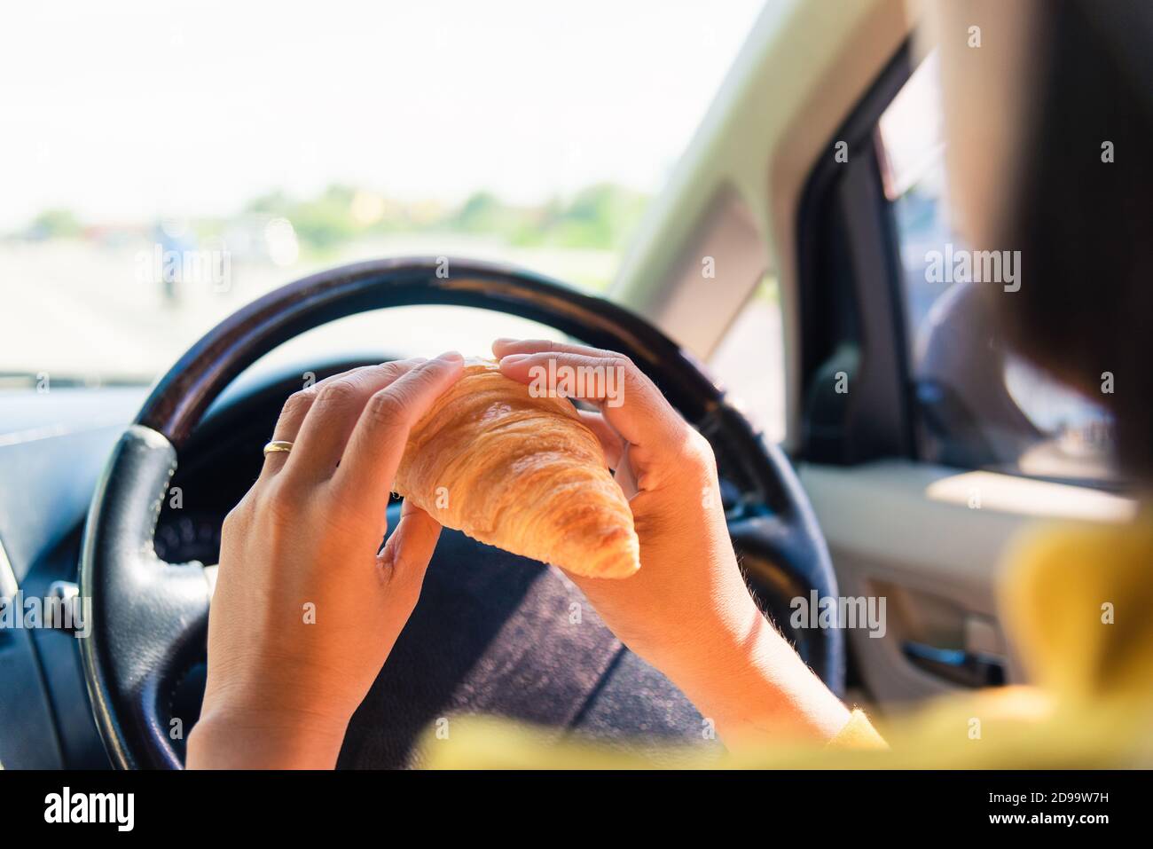 Asian woman eating food fastfood while driving the car in the morning ...