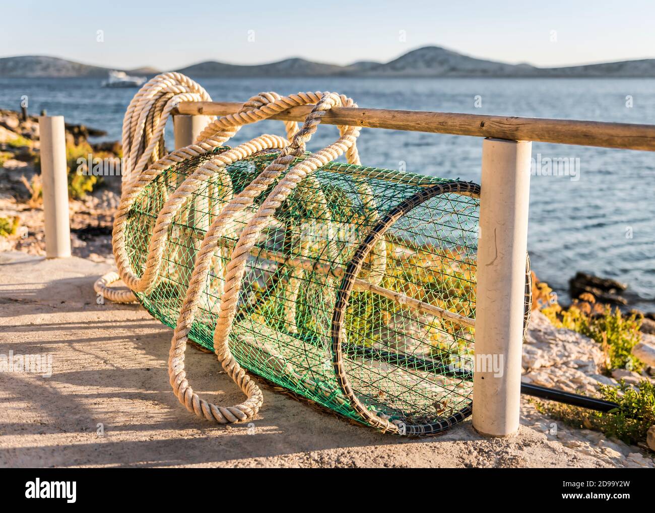 Cylindrical fish trap with ropes drying on the shore near the village ...