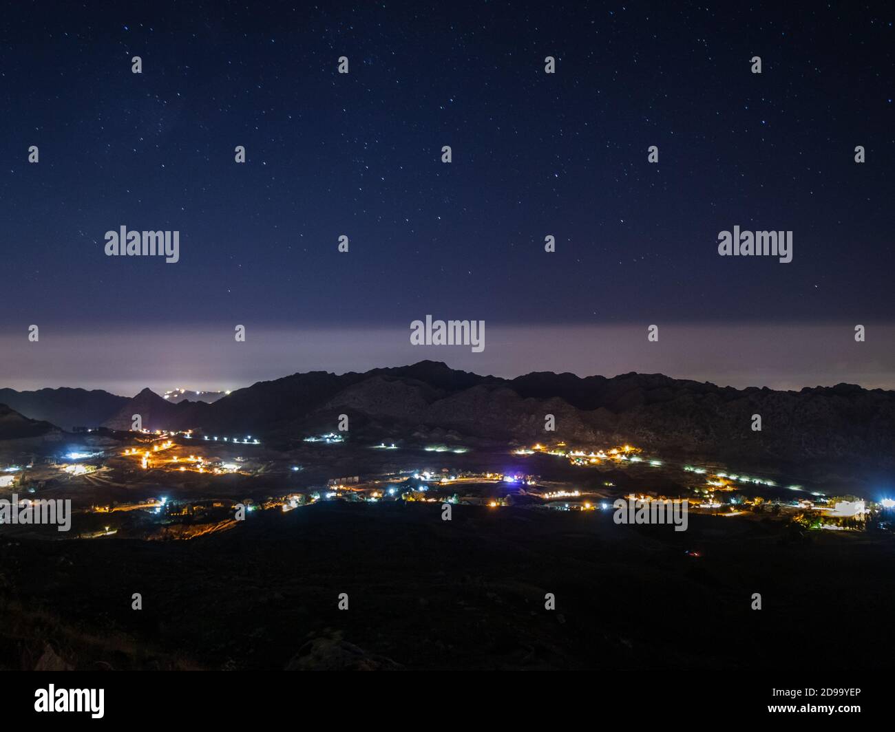 sky full of stars above a mountain range and town of LaqLouq in lebanon ...