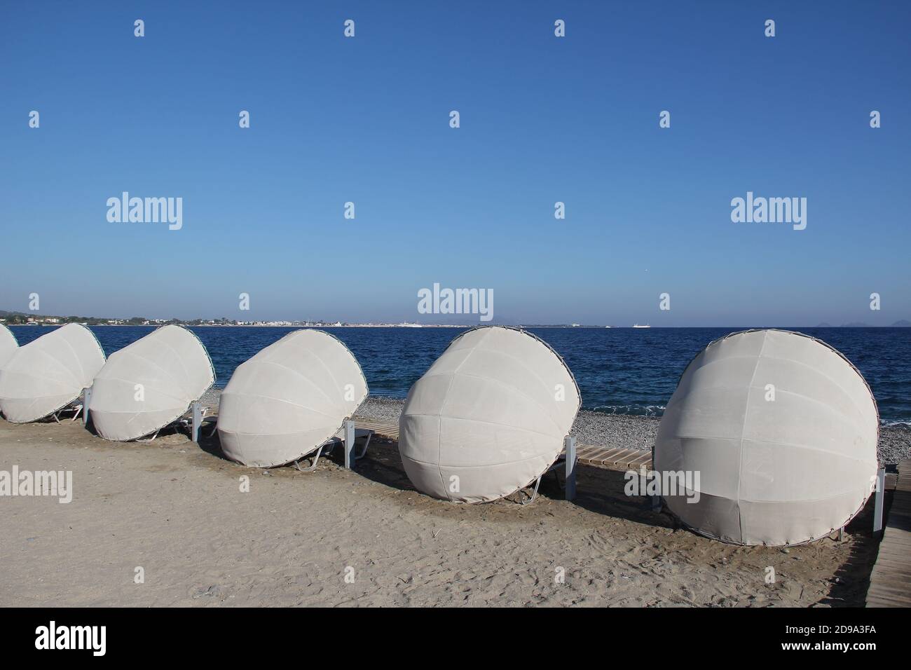 Row of sun beds with white dome covers on a beach at Kos Island in ...