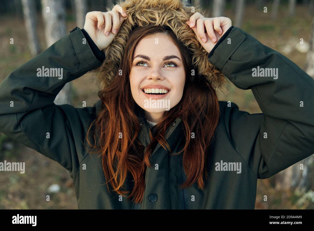 Woman in hooded jacket looks up arms over head nature fresh air Stock ...