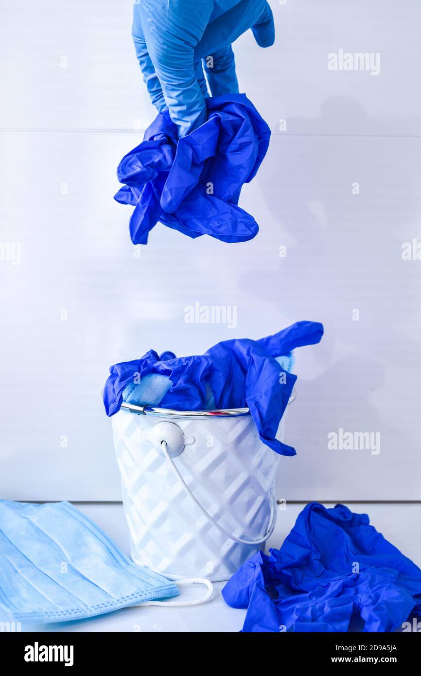 Hand throwing away used infectious masks and medical glove in the trash ...
