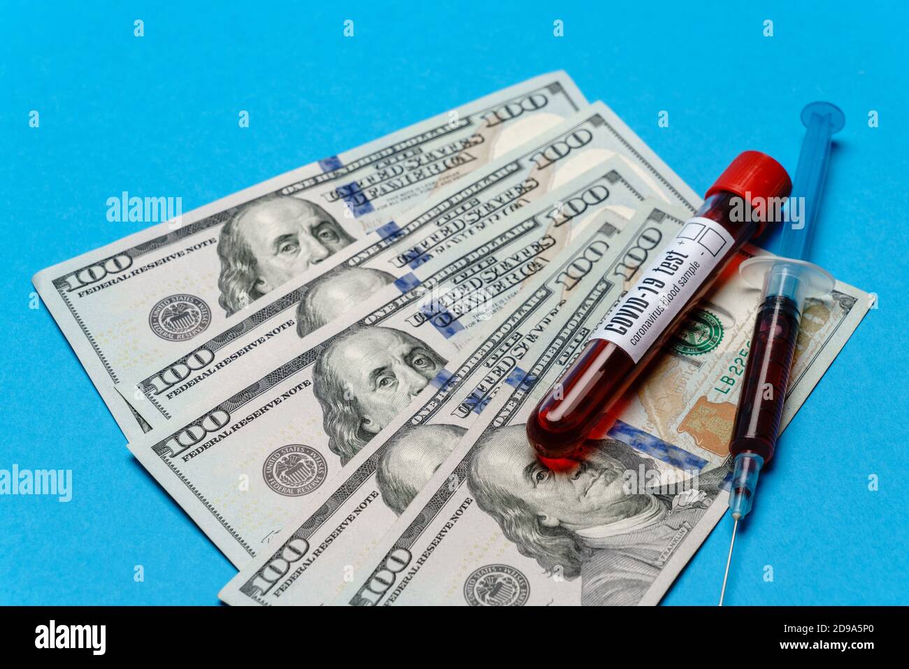 Close up 100 US dollar bills and blood sample in test tube over blue ...