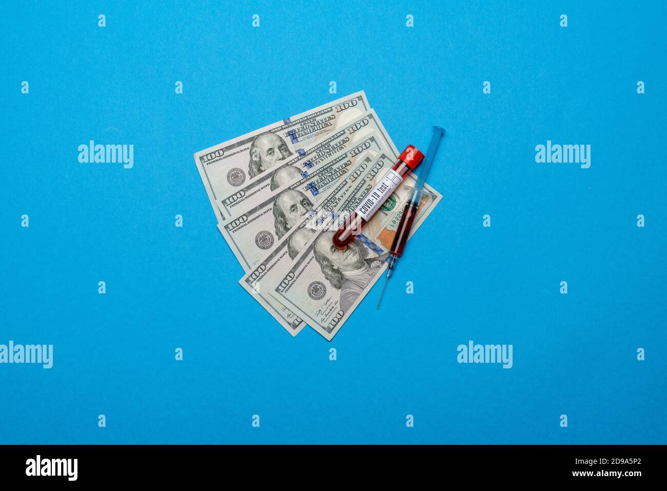 Close up 100 US dollar bills and blood sample in test tube over blue ...