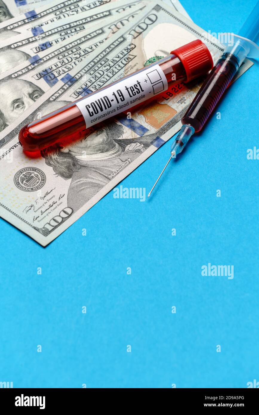 Close up 100 US dollar bills and blood sample in test tube over blue ...