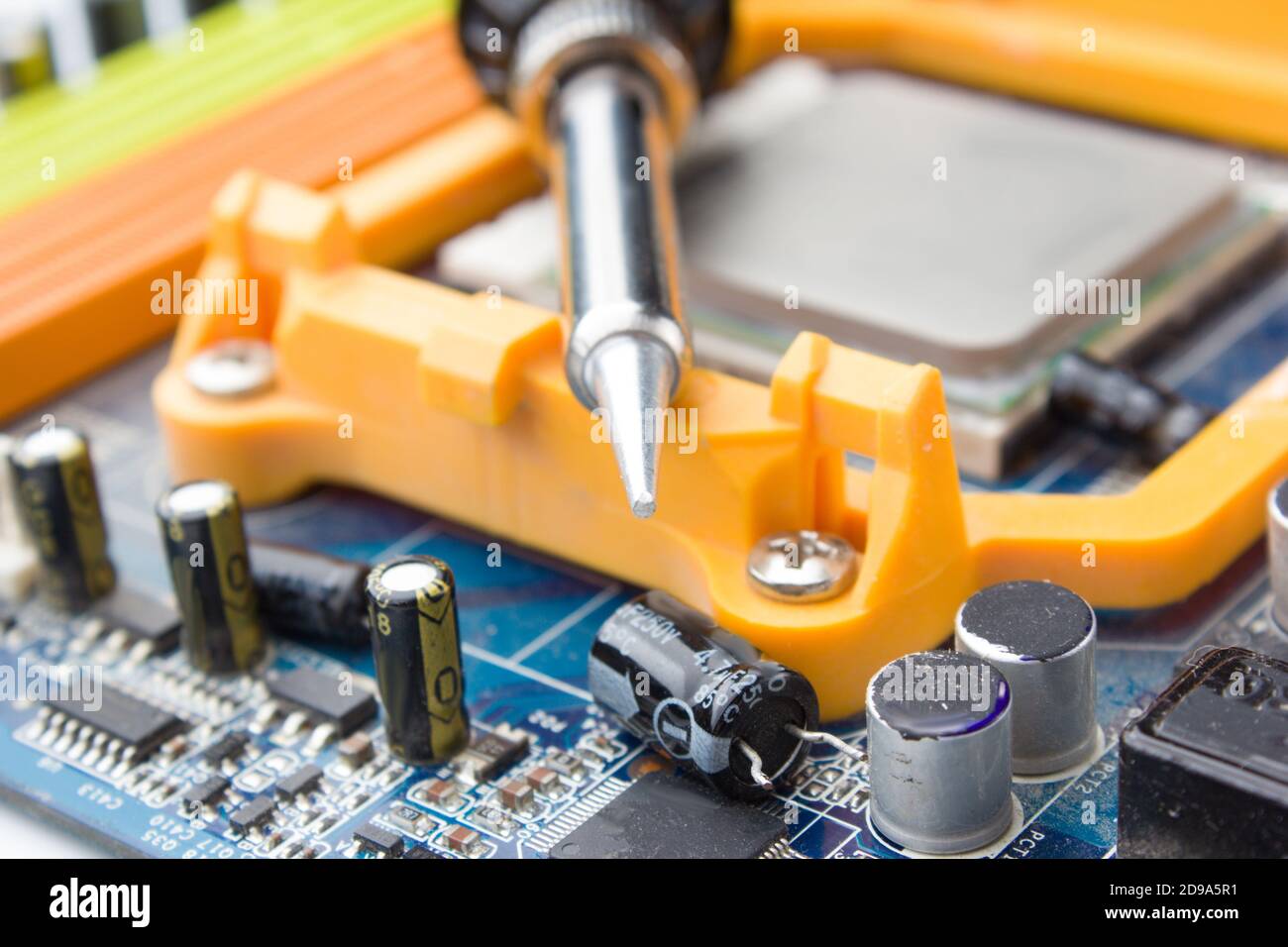soldering iron on the background of a computer Board and capacitors in ...